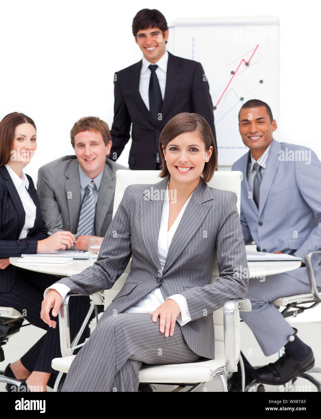 Assertive female executive sitting in front of her team in a meeting ...