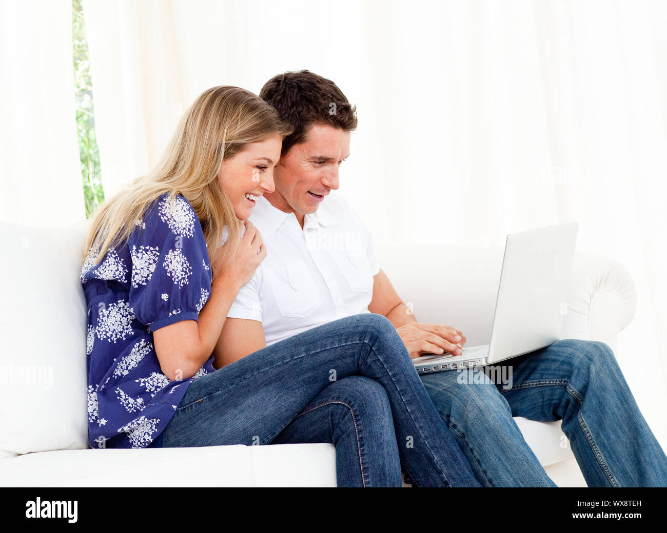 Animated couple using a laptop sitting on sofa at home Stock Photo - Alamy