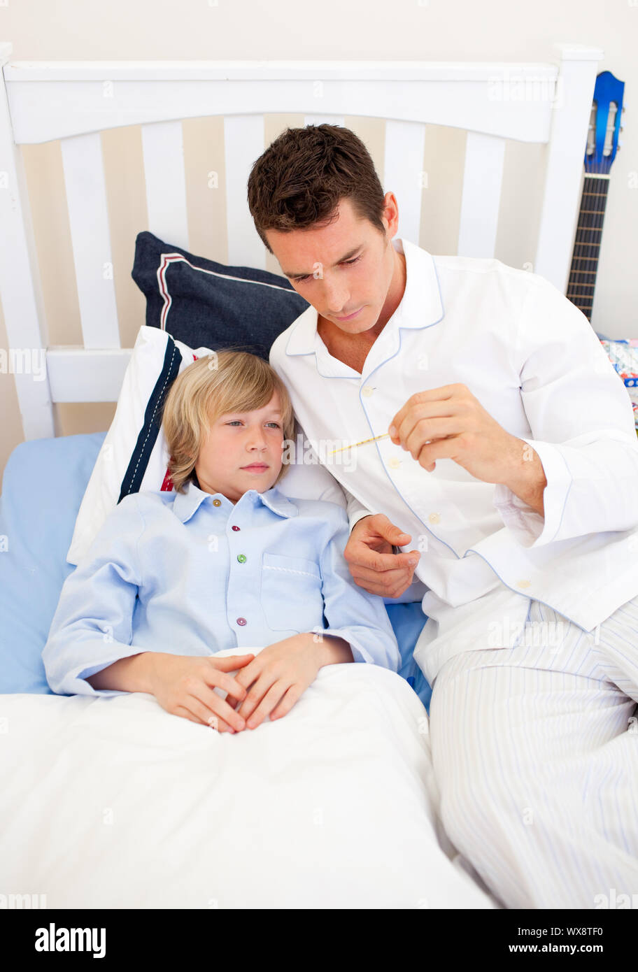Attractive father checking his son's temperature in the bedroom Stock ...