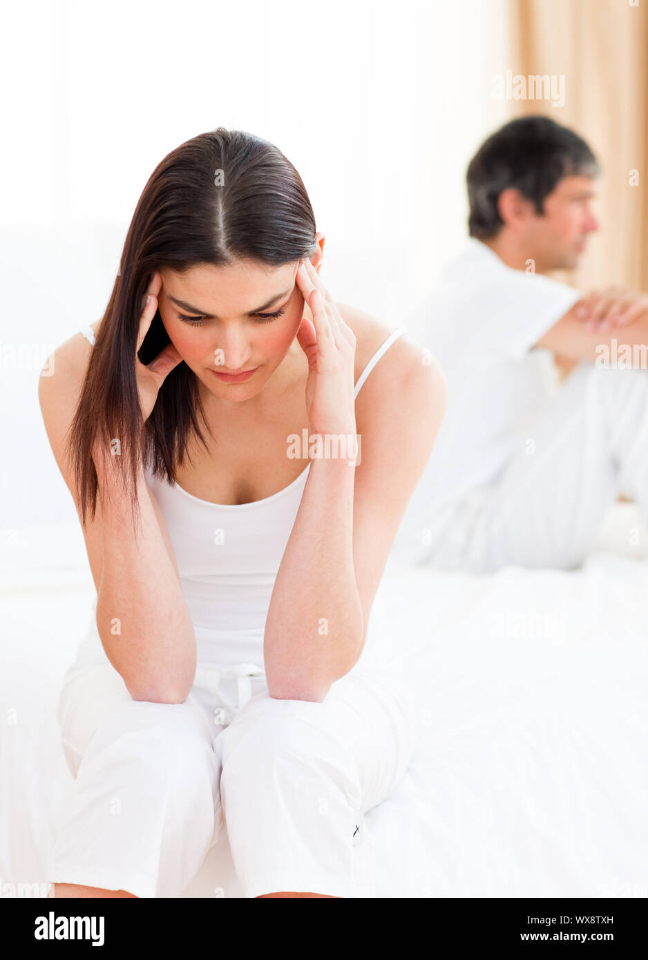 Distress couple sitting sitting separately on their bed after having a ...