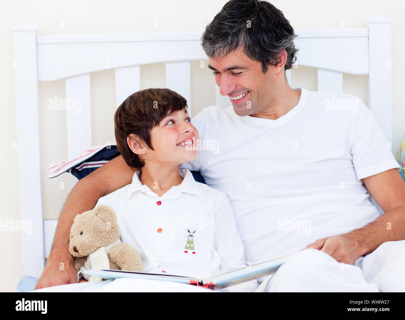 Attentive father reading with his son sitting on a bed Stock Photo - Alamy