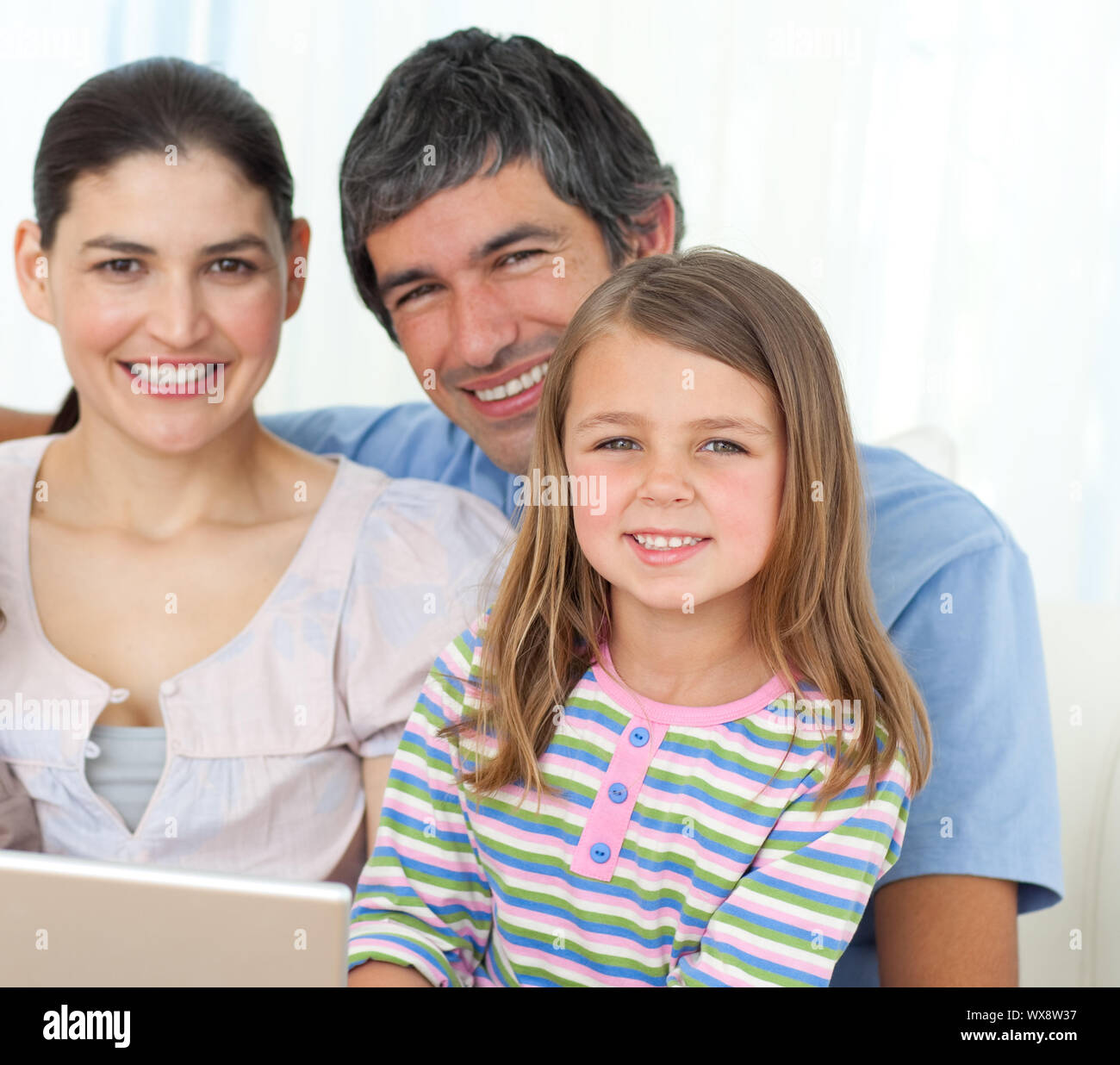 Little girl using a laptop with her parents on the sofa Stock Photo - Alamy