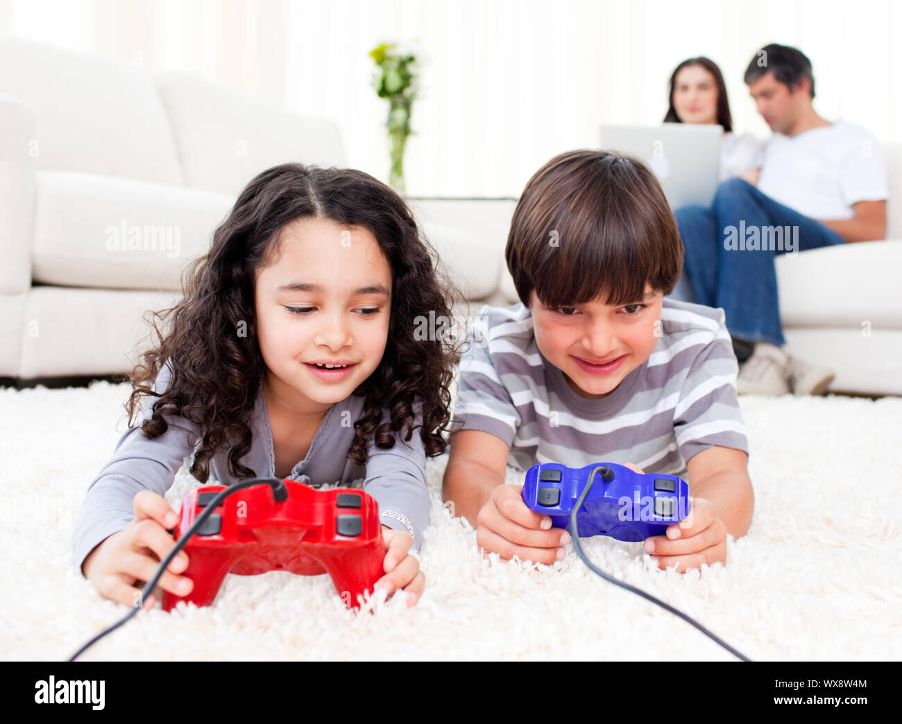 Cute siblings playing video games laying down on the floor in the ...