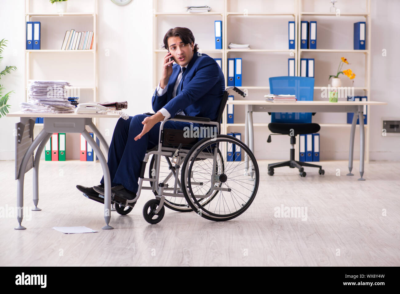 Young male employee in wheelchair working in the office Stock Photo - Alamy