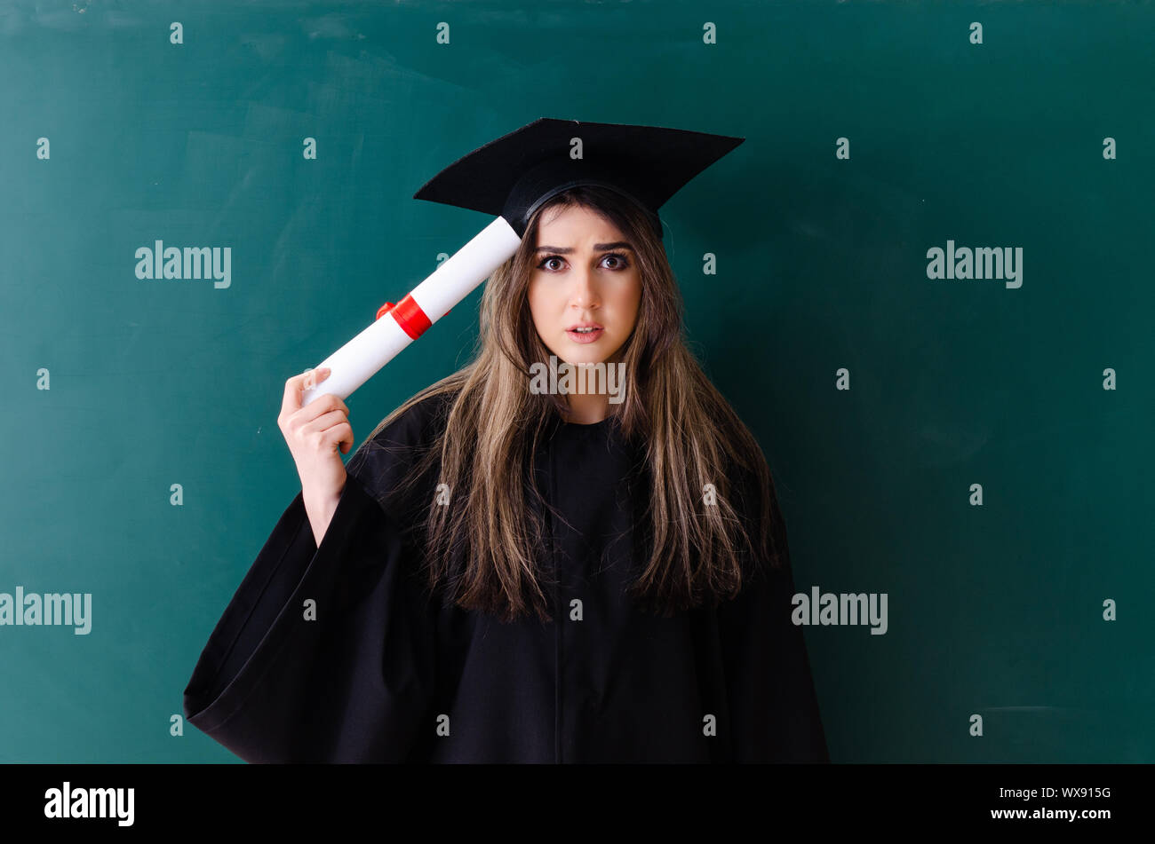 Female graduate student in front of green board Stock Photo - Alamy