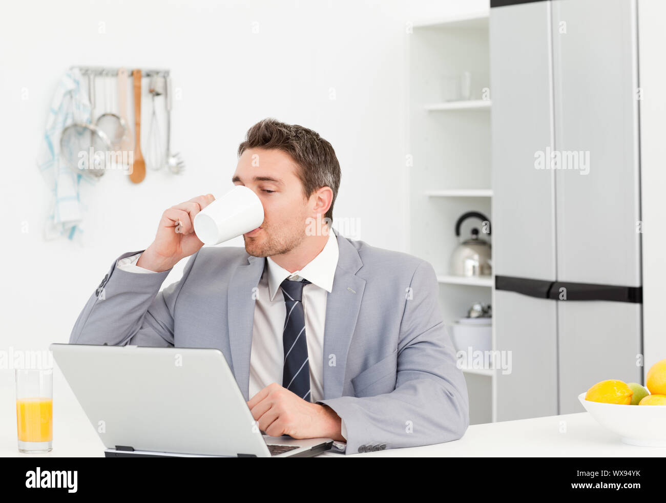 Businessman drinking while he is looking at his laptop at home Stock ...