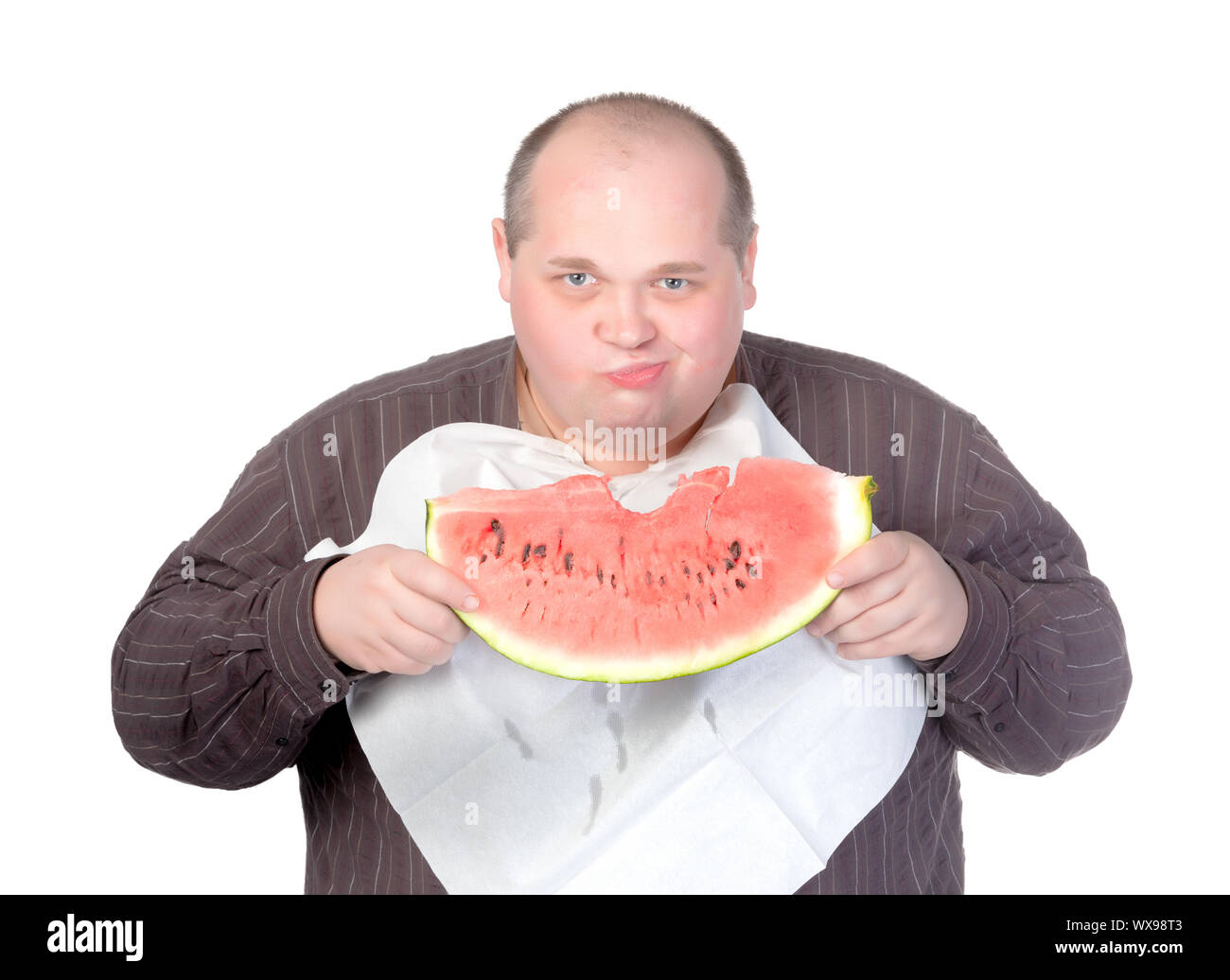 Obese man with a serviette bib around his neck standing eating a large ...