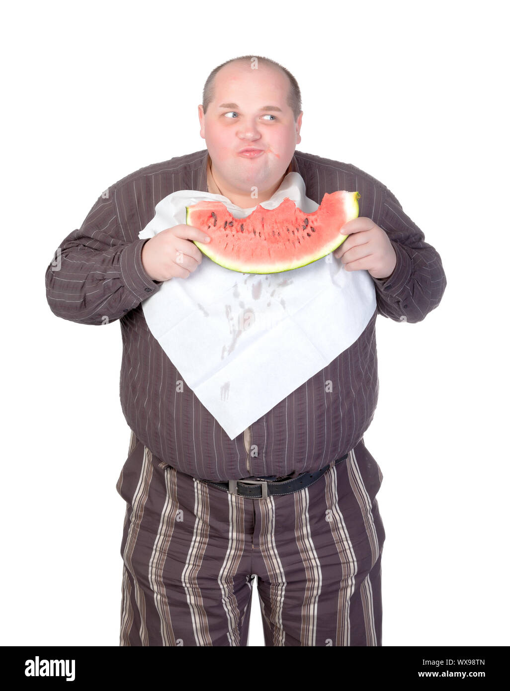 Obese man with a serviette bib around his neck standing eating a large ...