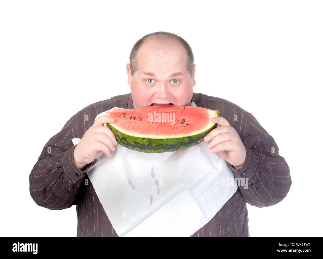 Obese man with a serviette bib around his neck standing eating a large ...