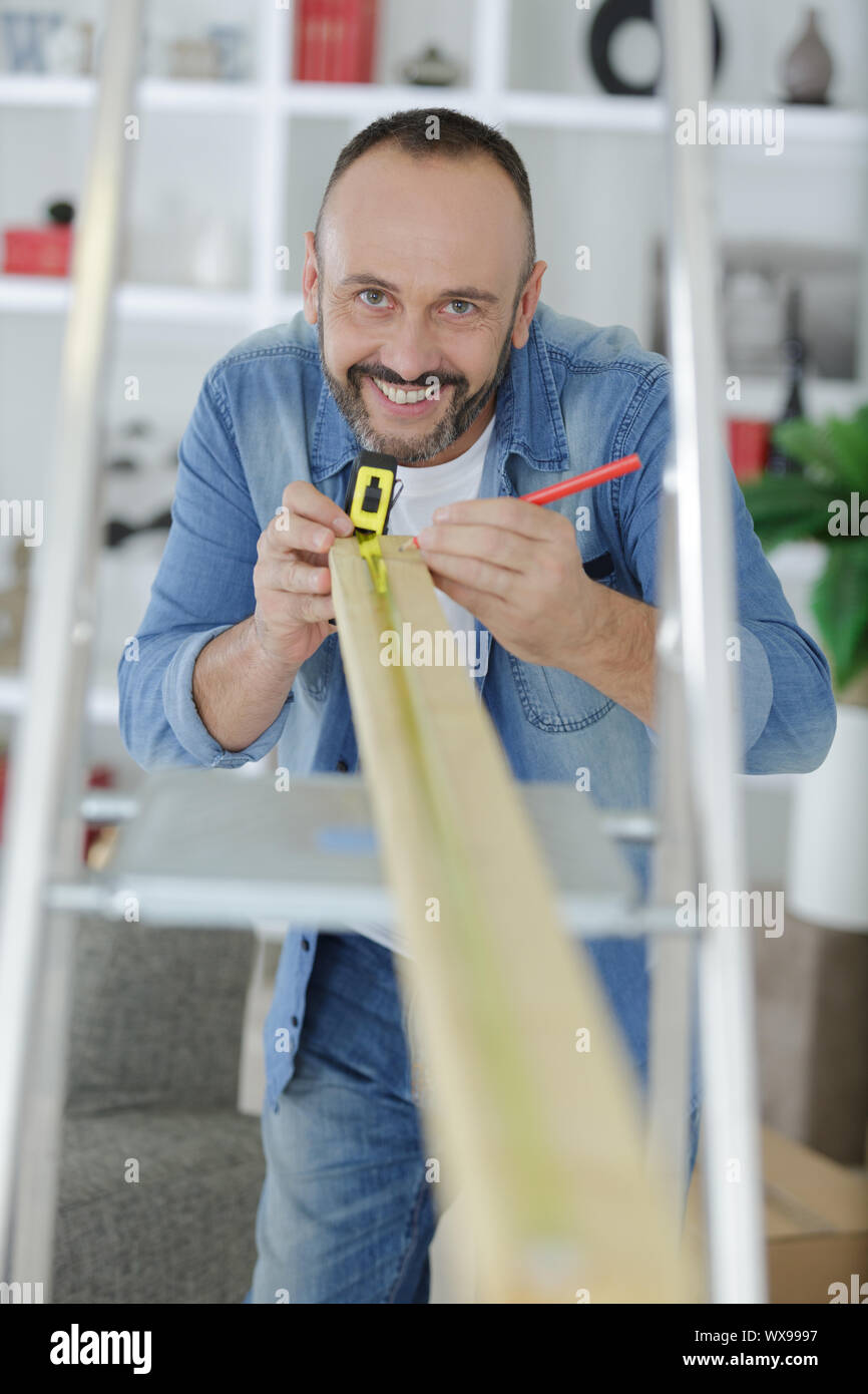 happy man measuring wood piece for furniture assembling Stock Photo - Alamy