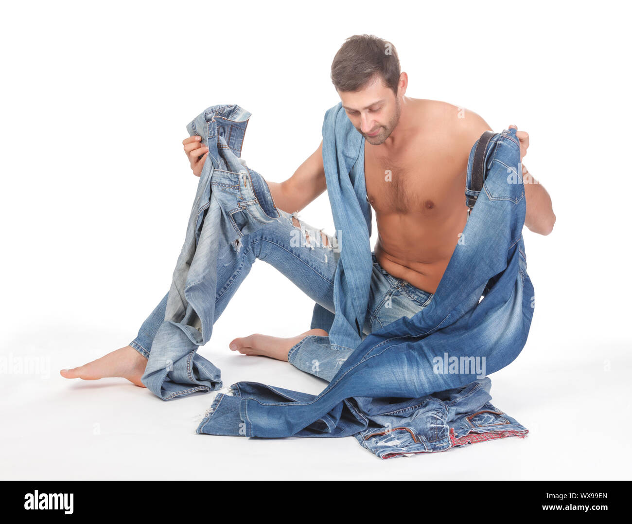 Cool shirtless trendy man in a pair of modern ragged jeans sitting ...