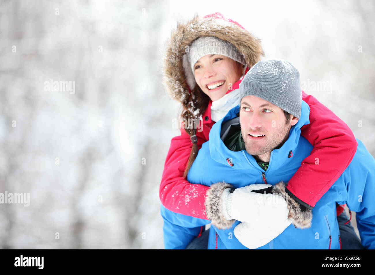 Happy winter travel couple. Man giving woman piggyback ride on winter ...