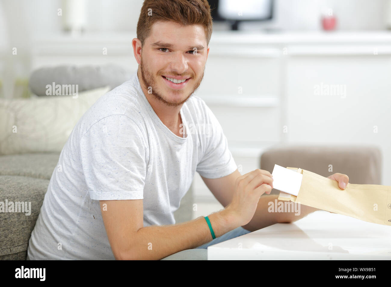 portrait of young man taking letter from envelope Stock Photo - Alamy