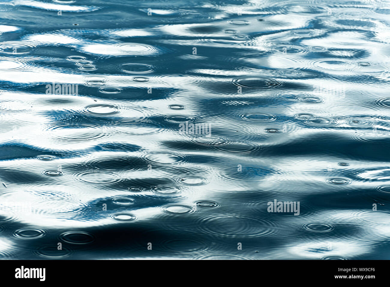 Rain drops falling on lake surface nice dark blue color Stock Photo - Alamy