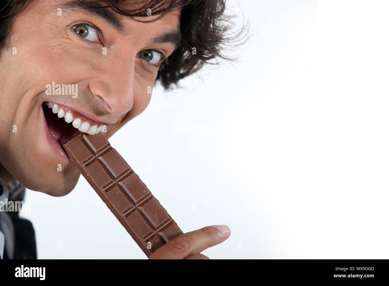 Excited man eating chocolate bar Stock Photo - Alamy