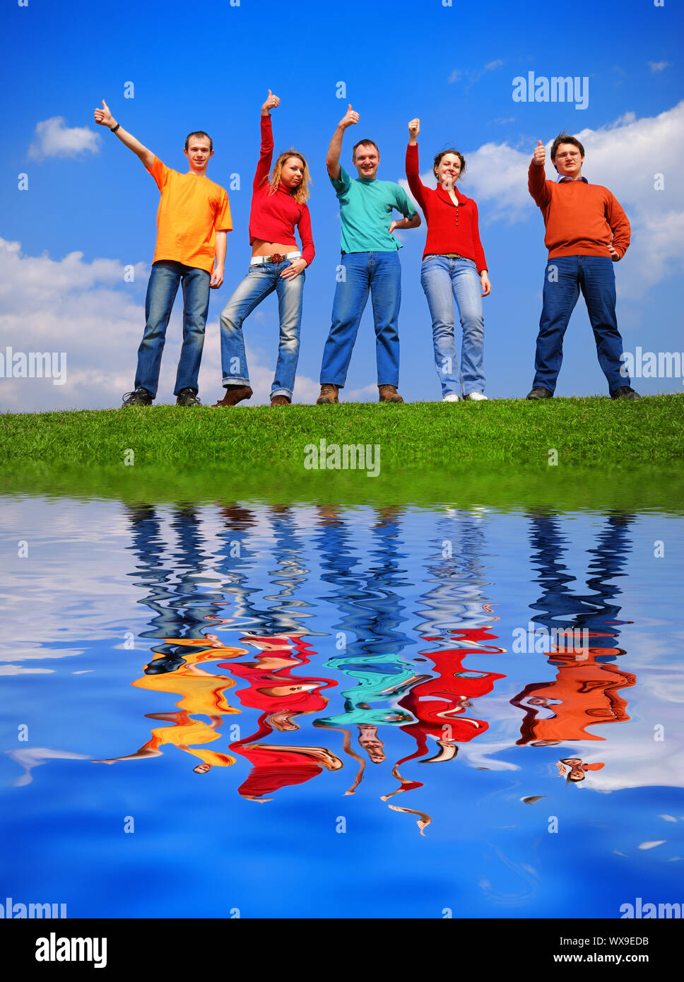 Group of people with thumbs up against blue sky with reflection on ...