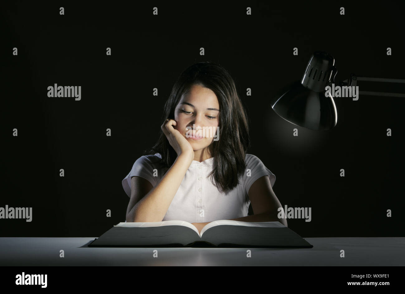 Young girl student, studying late into the night with her book and ...