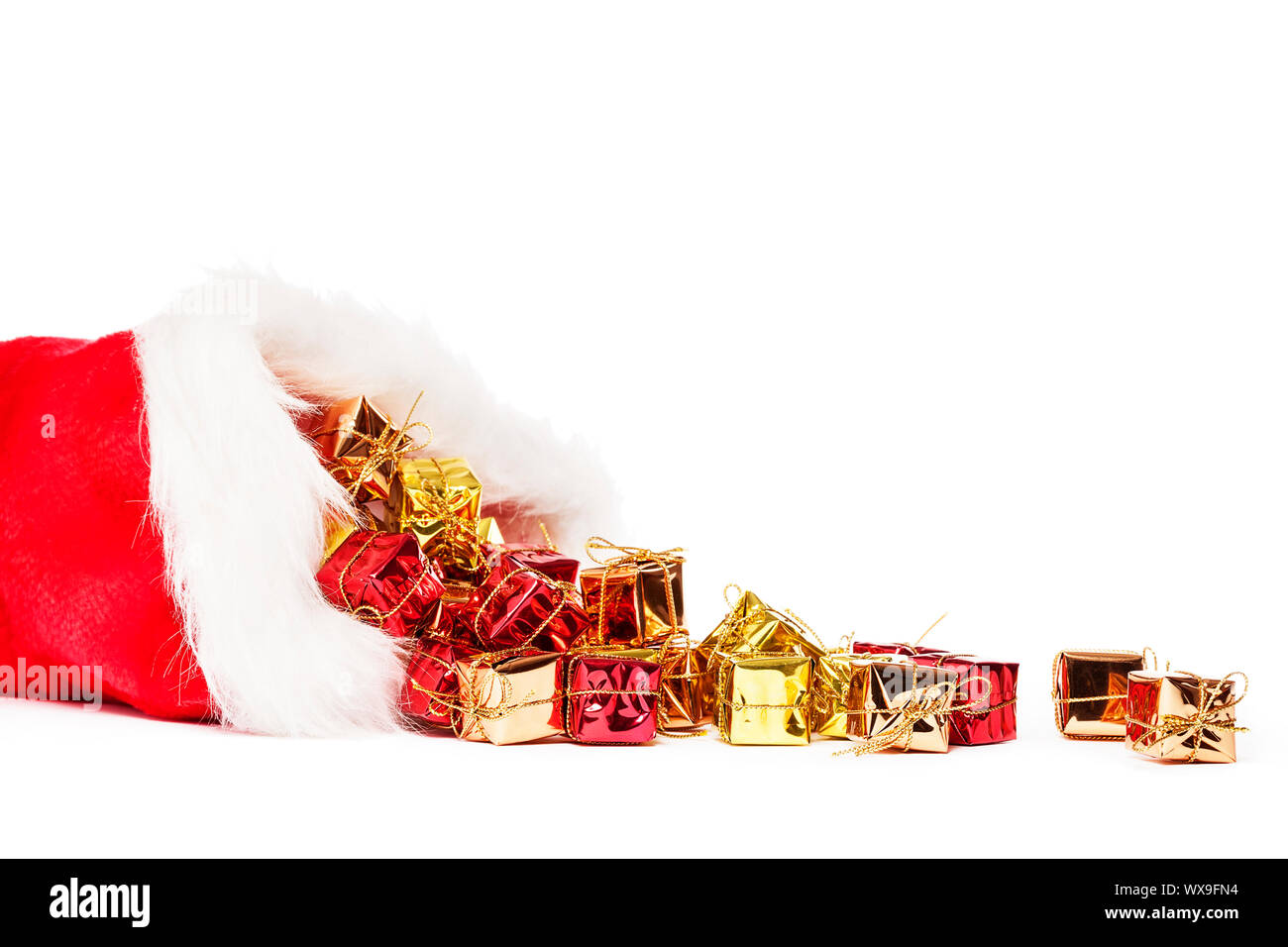 small colorful christmas presents falling from santas hat on white ...