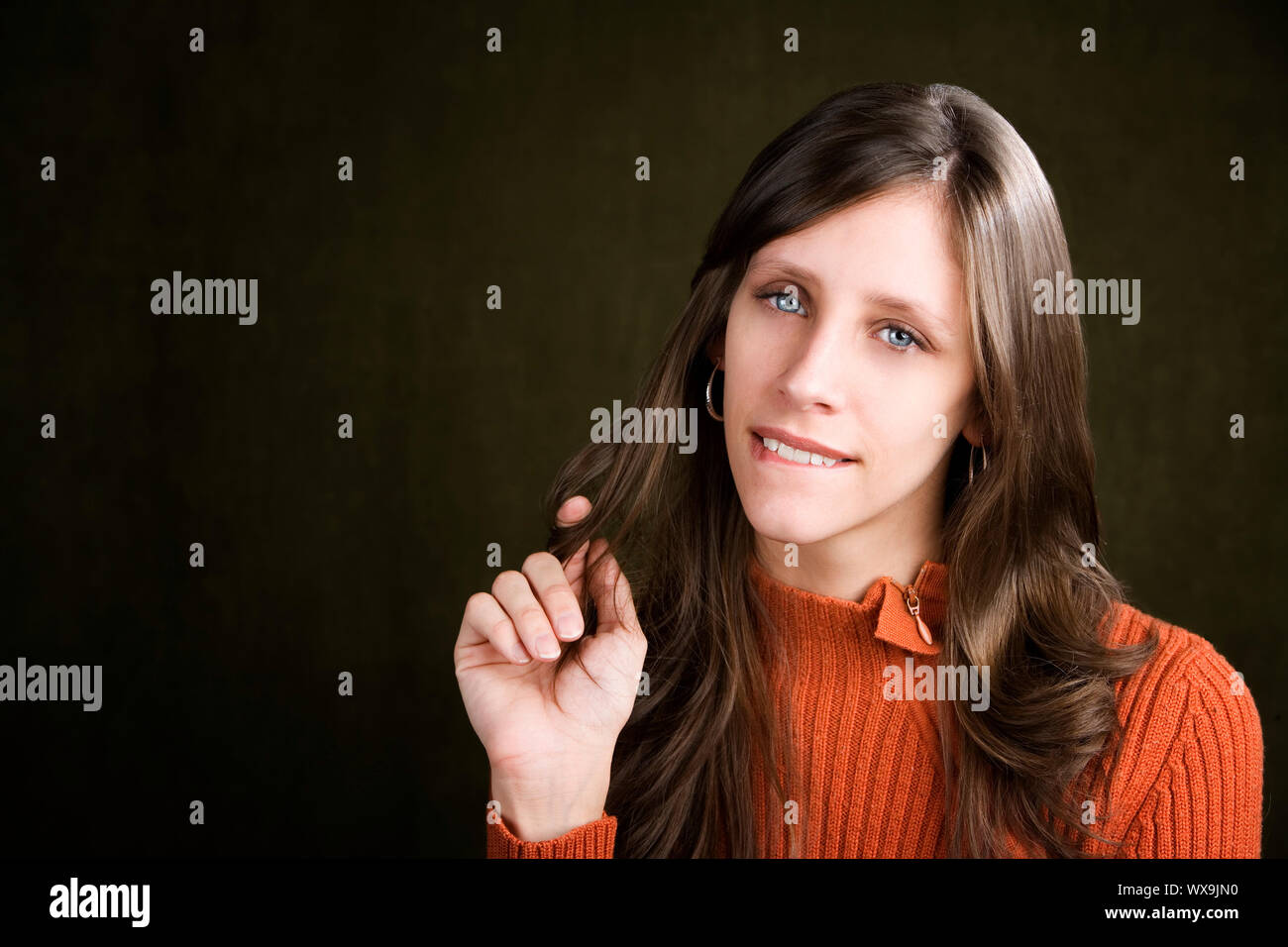Pretty Young Woman Biting Her Lip and Twirling Her Hair Stock Photo - Alamy