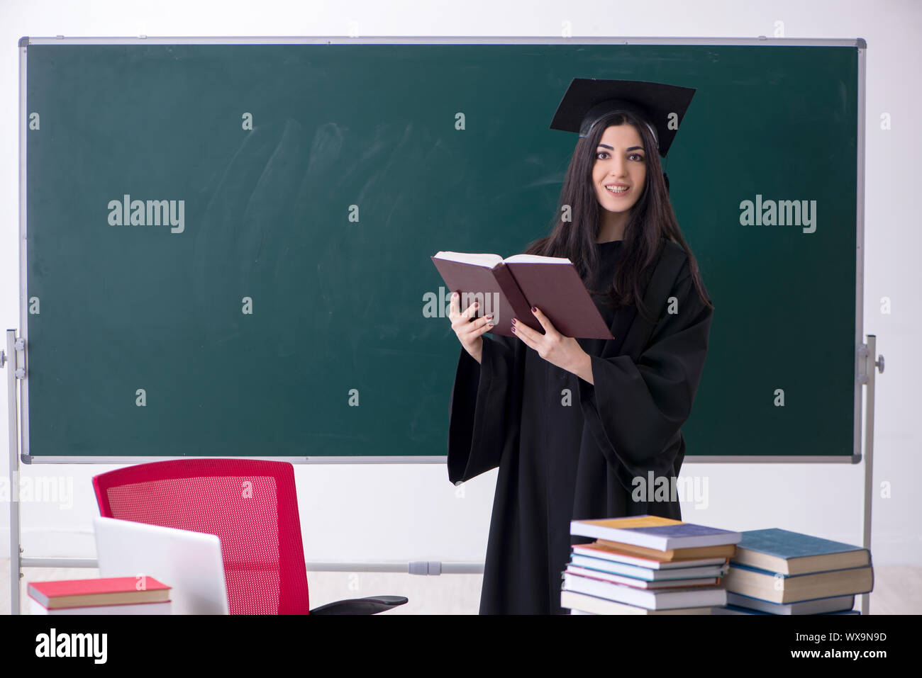 Female graduate student in front of green board Stock Photo - Alamy