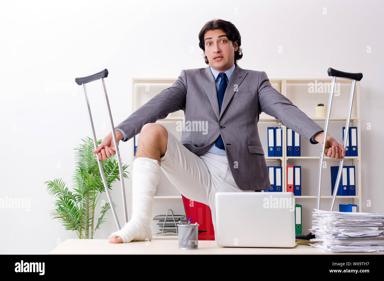 Leg injured employee working in the office Stock Photo - Alamy