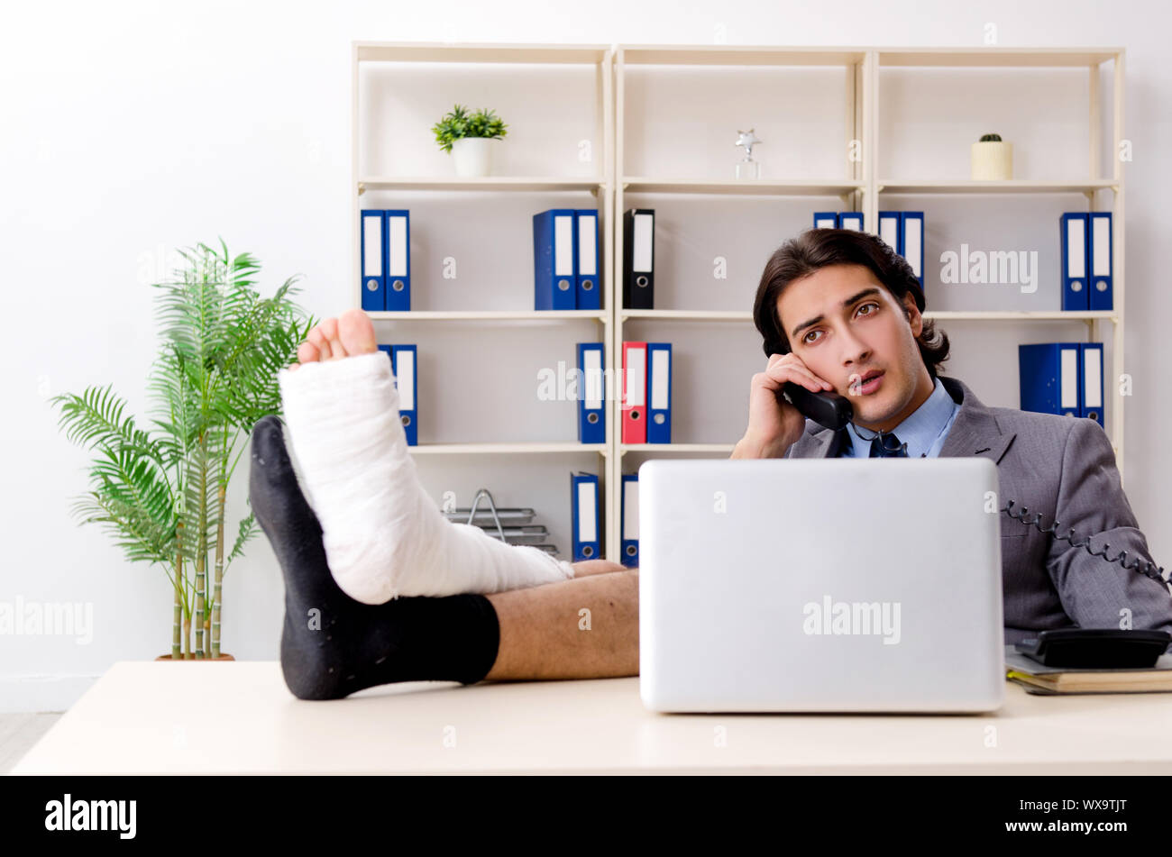 Leg injured employee working in the office Stock Photo - Alamy