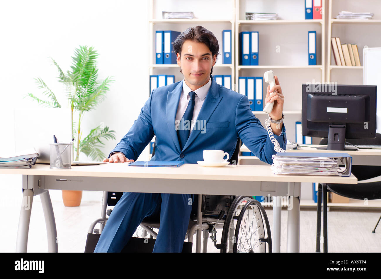 Male employee in wheelchair working at the office Stock Photo - Alamy