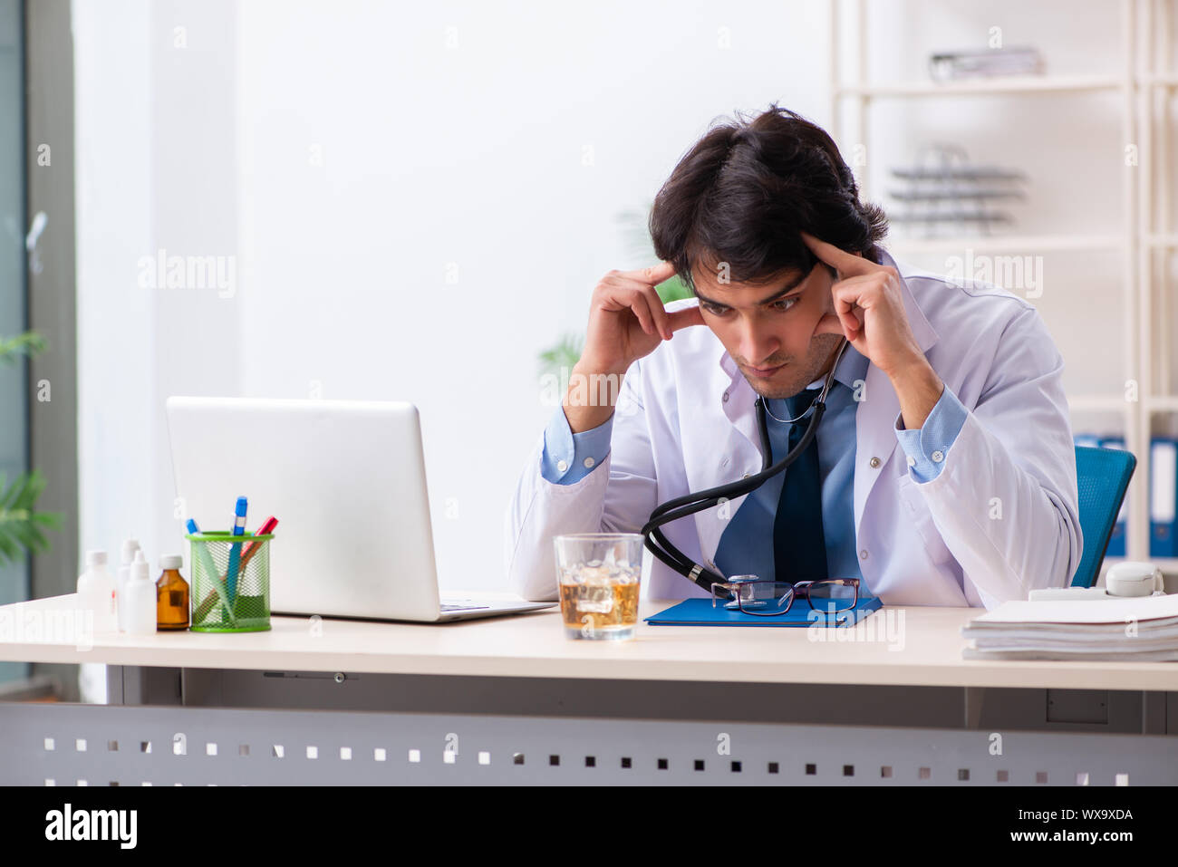 Young male doctor drinking in the office Stock Photo - Alamy