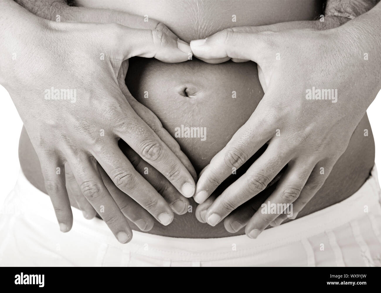 Pregnant women wrap her arms around the belly in the form of the heart ...