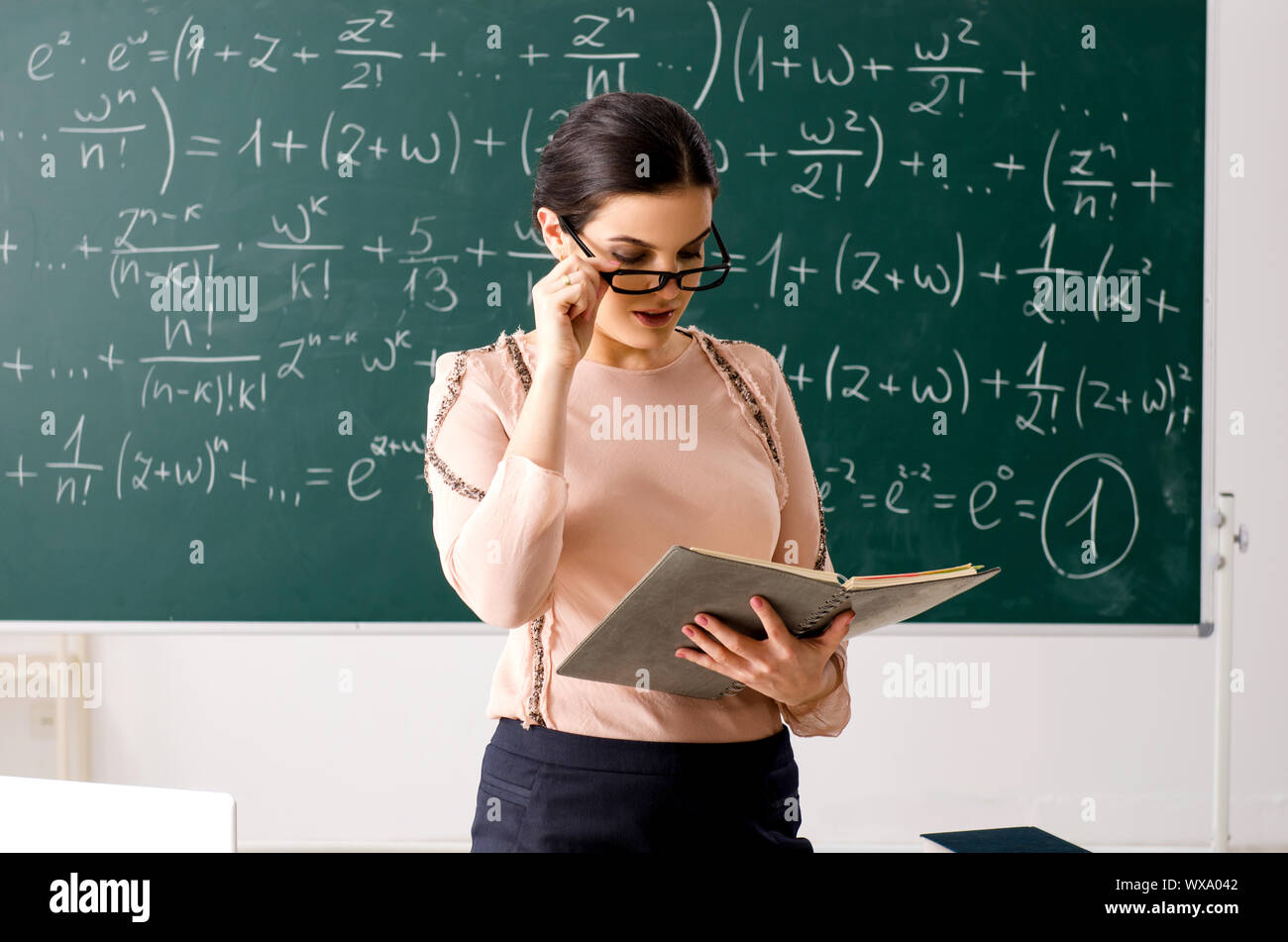 Female teacher standing in front of chalkboard Stock Photo - Alamy