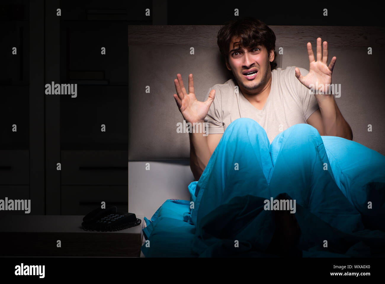 Young man scared in his bed having nightmares Stock Photo - Alamy
