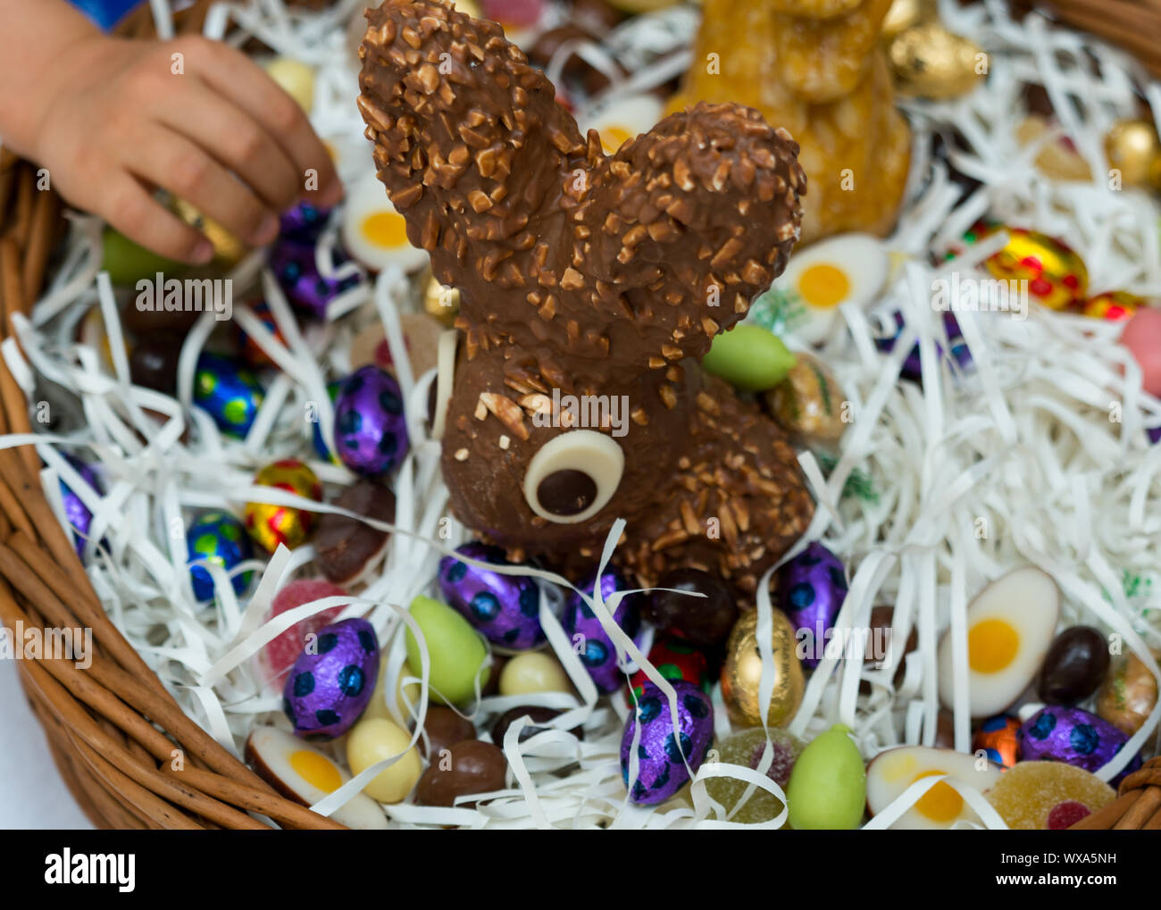 many children hands reach for sweets candy and chocolate in an Easter ...