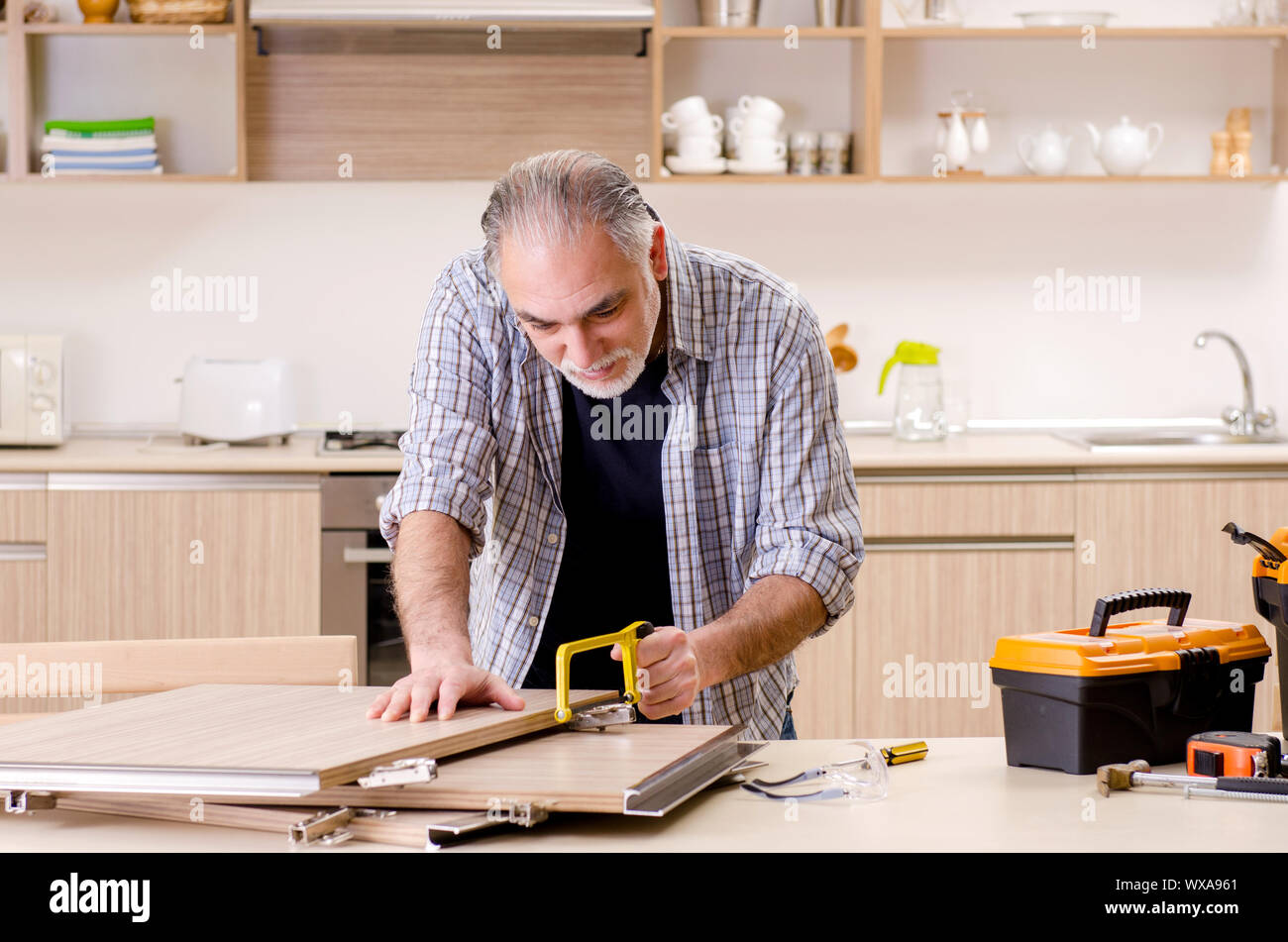 Mature repairman installing kitchen hi-res stock photography and images ...