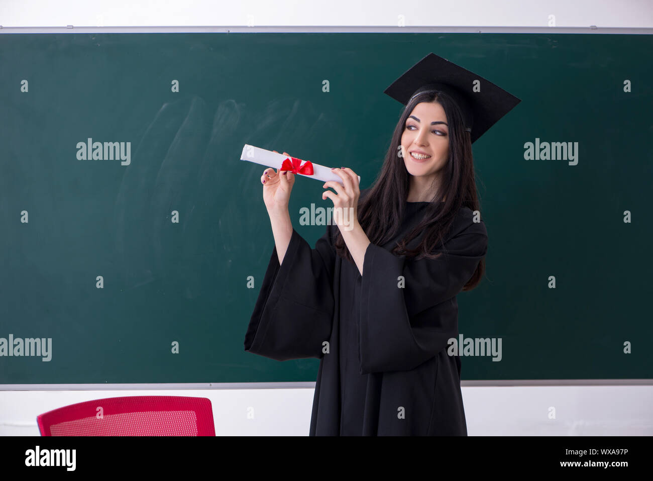 Female graduate student in front of green board Stock Photo - Alamy