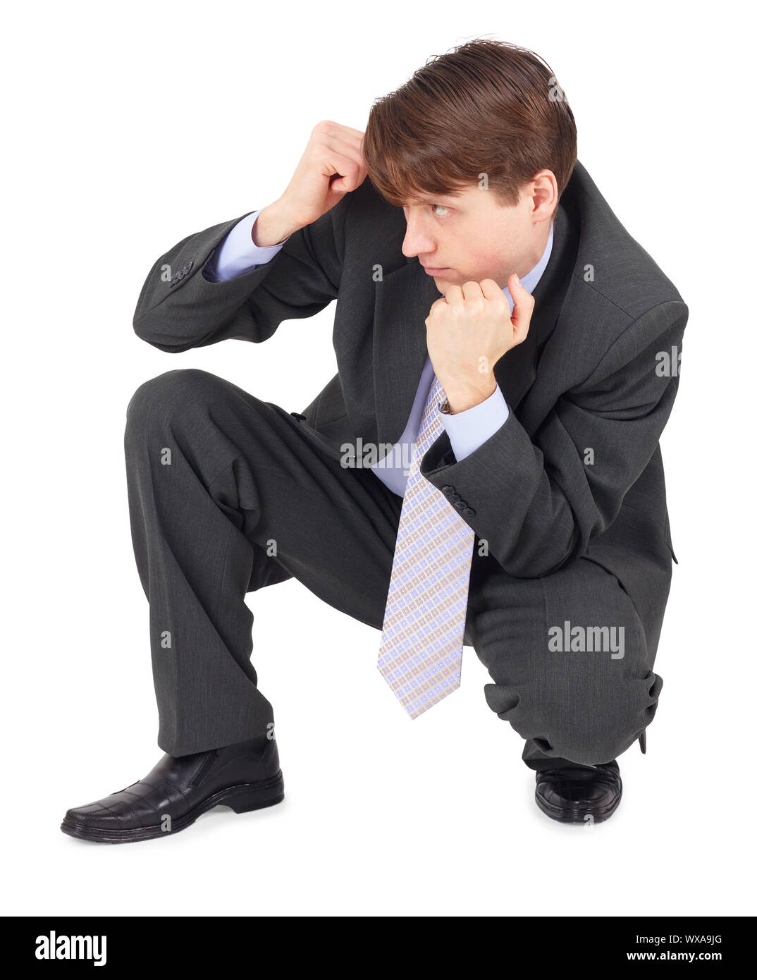 A young man sits in a defensive pose, isolated on a white background ...