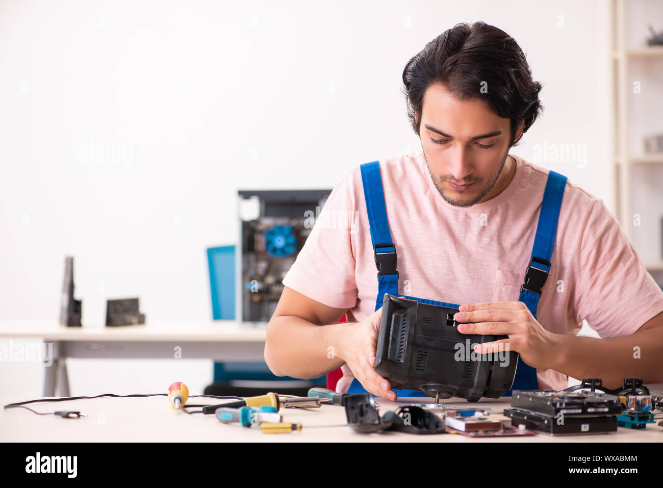 Young male contractor repairing computer Stock Photo - Alamy