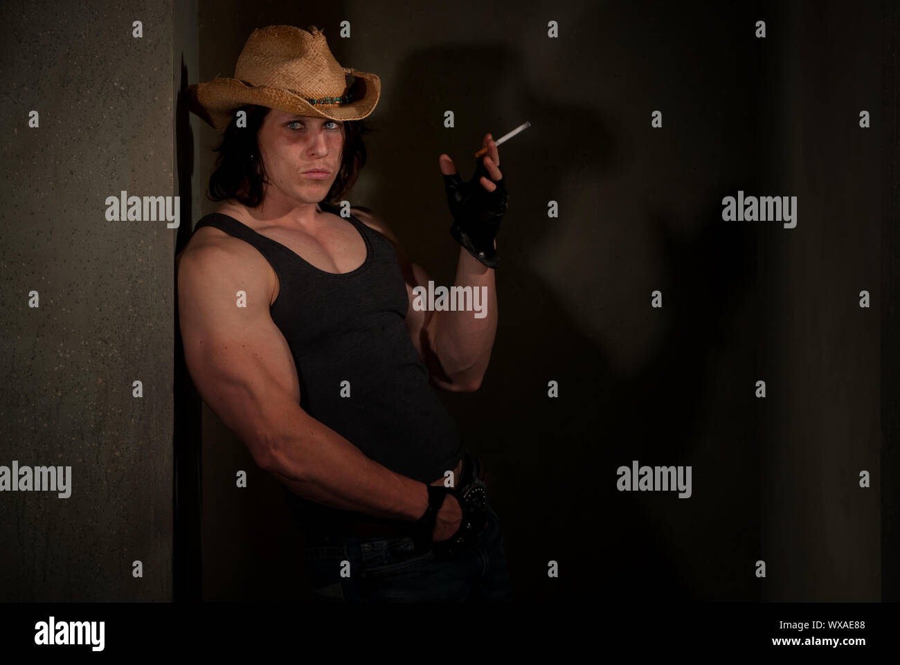 Smoking man in cowboy hat leaning on wall Stock Photo - Alamy