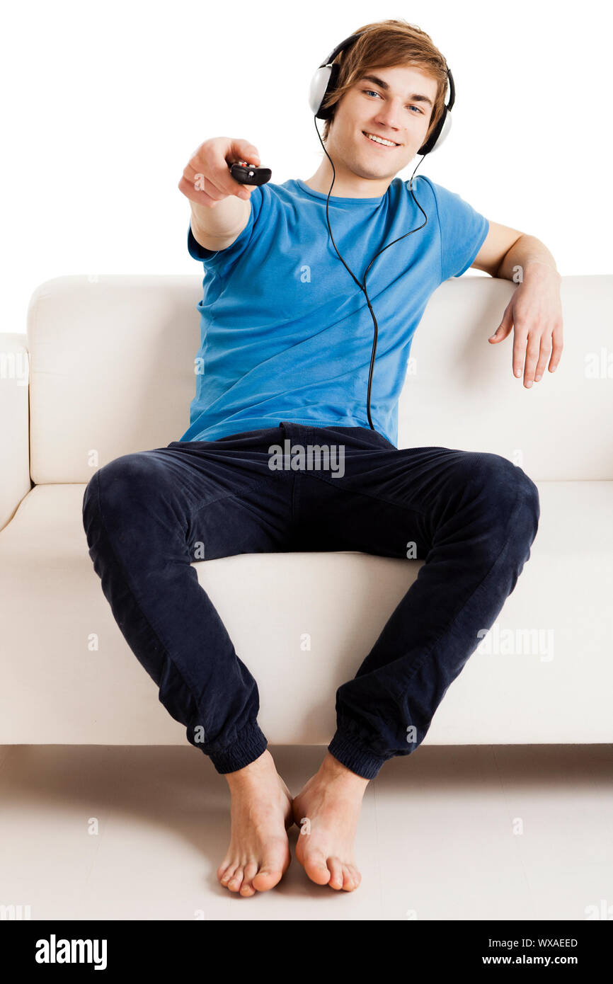 Young man sitting on the couch using a remote control Stock Photo - Alamy