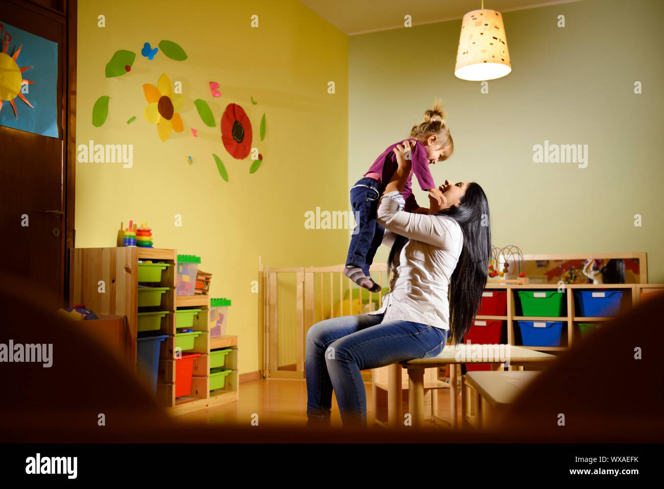 People having fun at school, female educator lifting mid-air child in ...