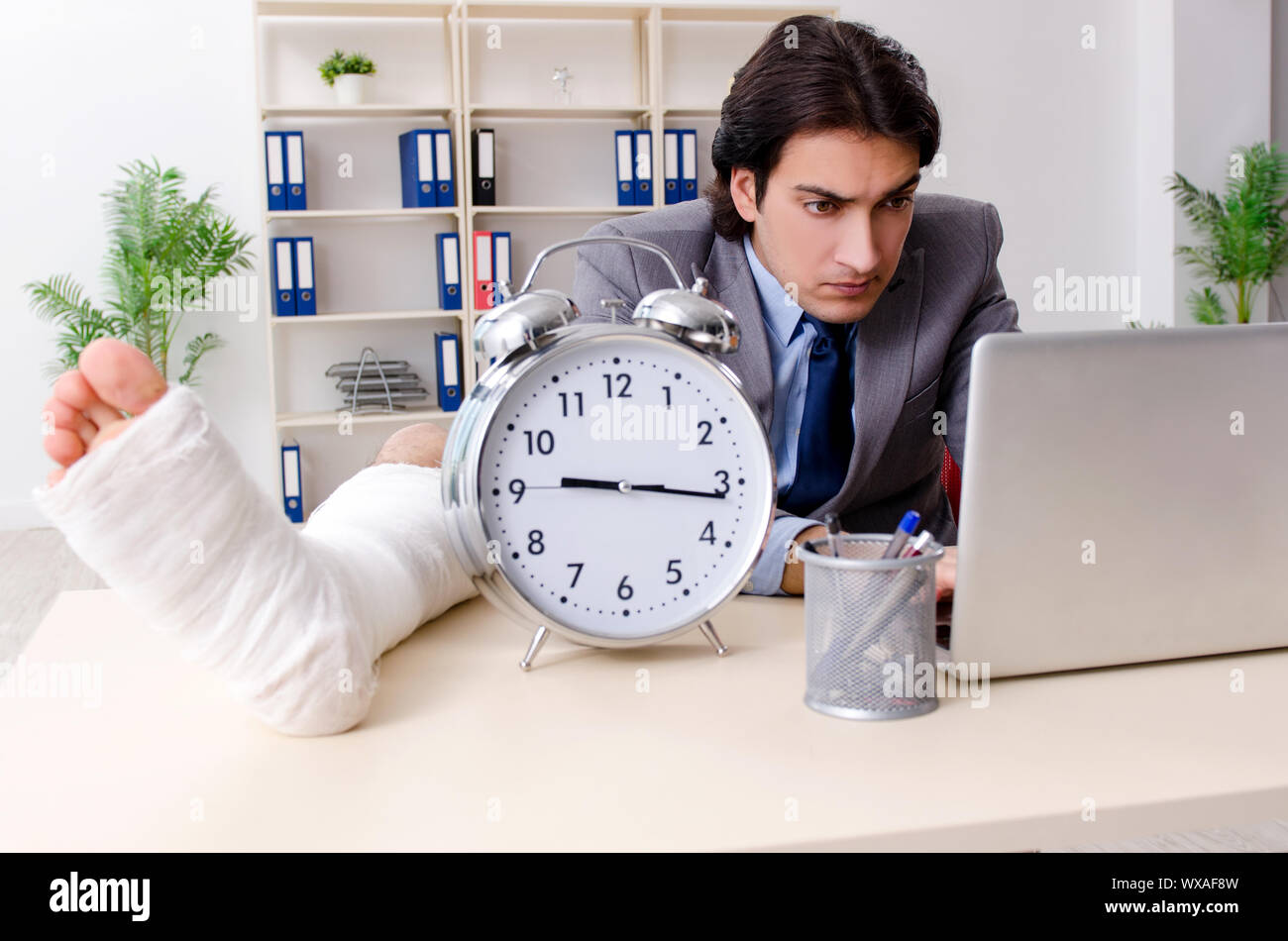 Leg injured employee working in the office Stock Photo - Alamy