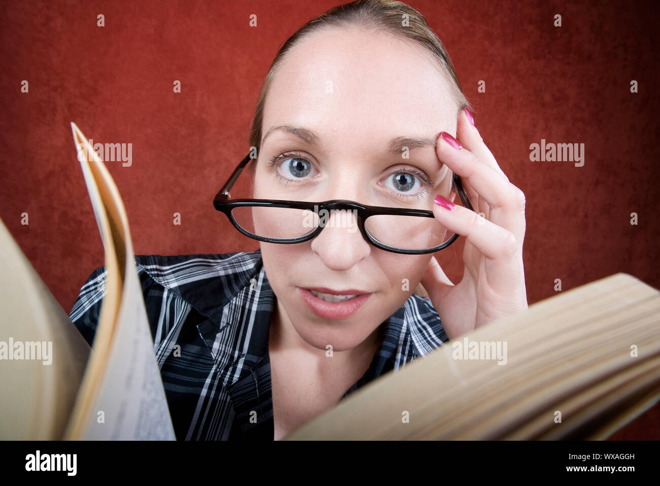 Perplexed woman with big eyes and glasses reading a book Stock Photo ...