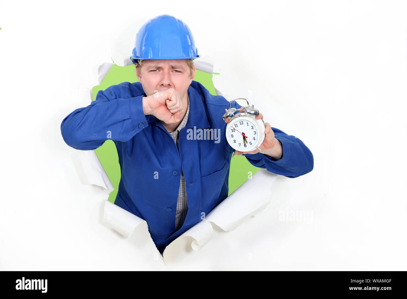 Tired manual worker holding alarm clock Stock Photo - Alamy
