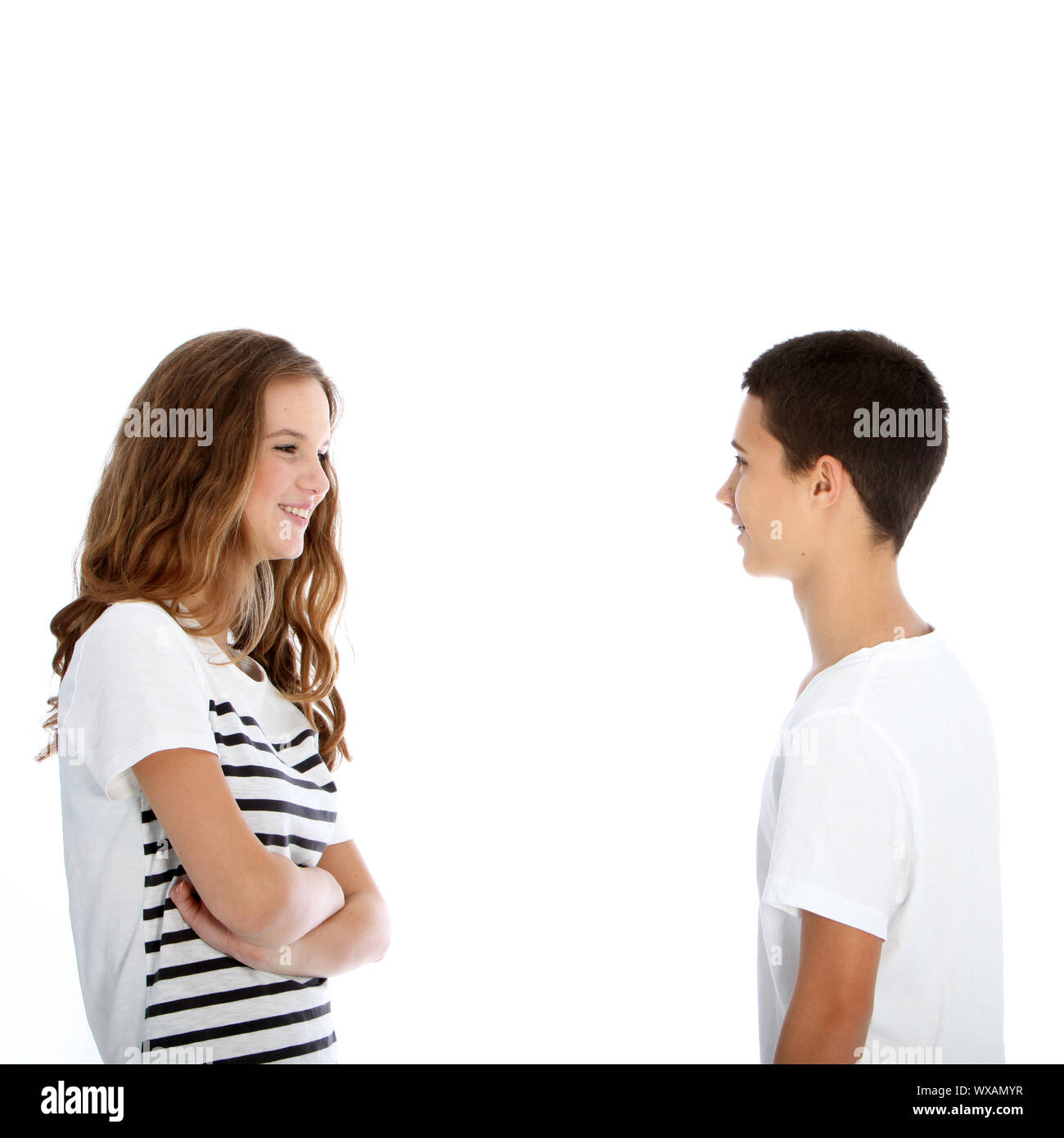 Attractive young teenage boy and girl standing sideways facing each ...