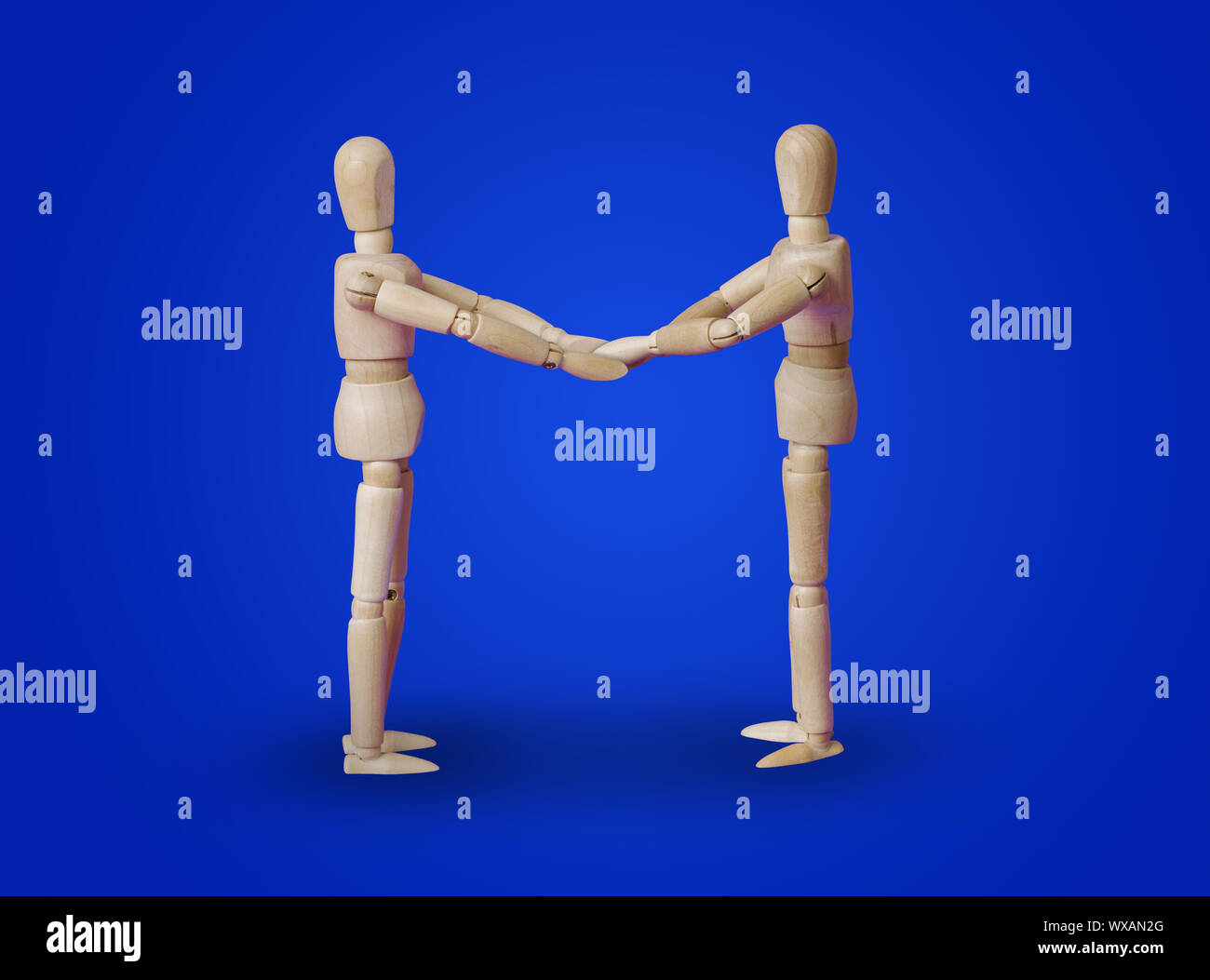 Wooden toy figures handshake on blue Stock Photo - Alamy