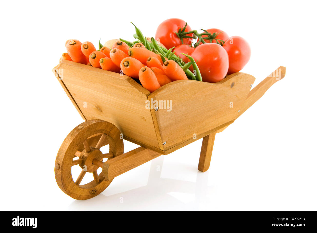 Wooden wheelbarrow filled with fresh vegetables on white background ...