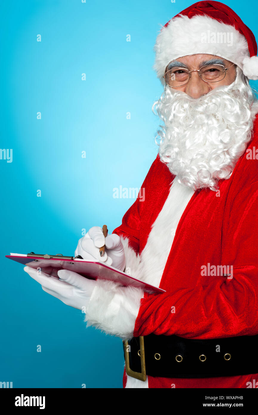Santa Claus making notes in the wish list and smiling at camera Stock ...