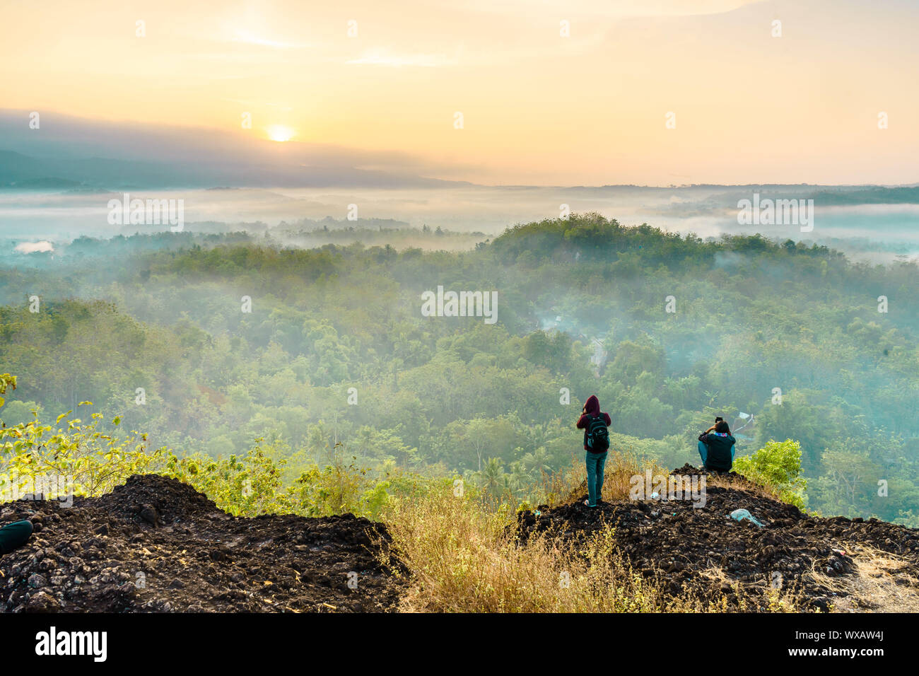 Tourists enjoying colorful sunrise with beautiful scenery and misty ...