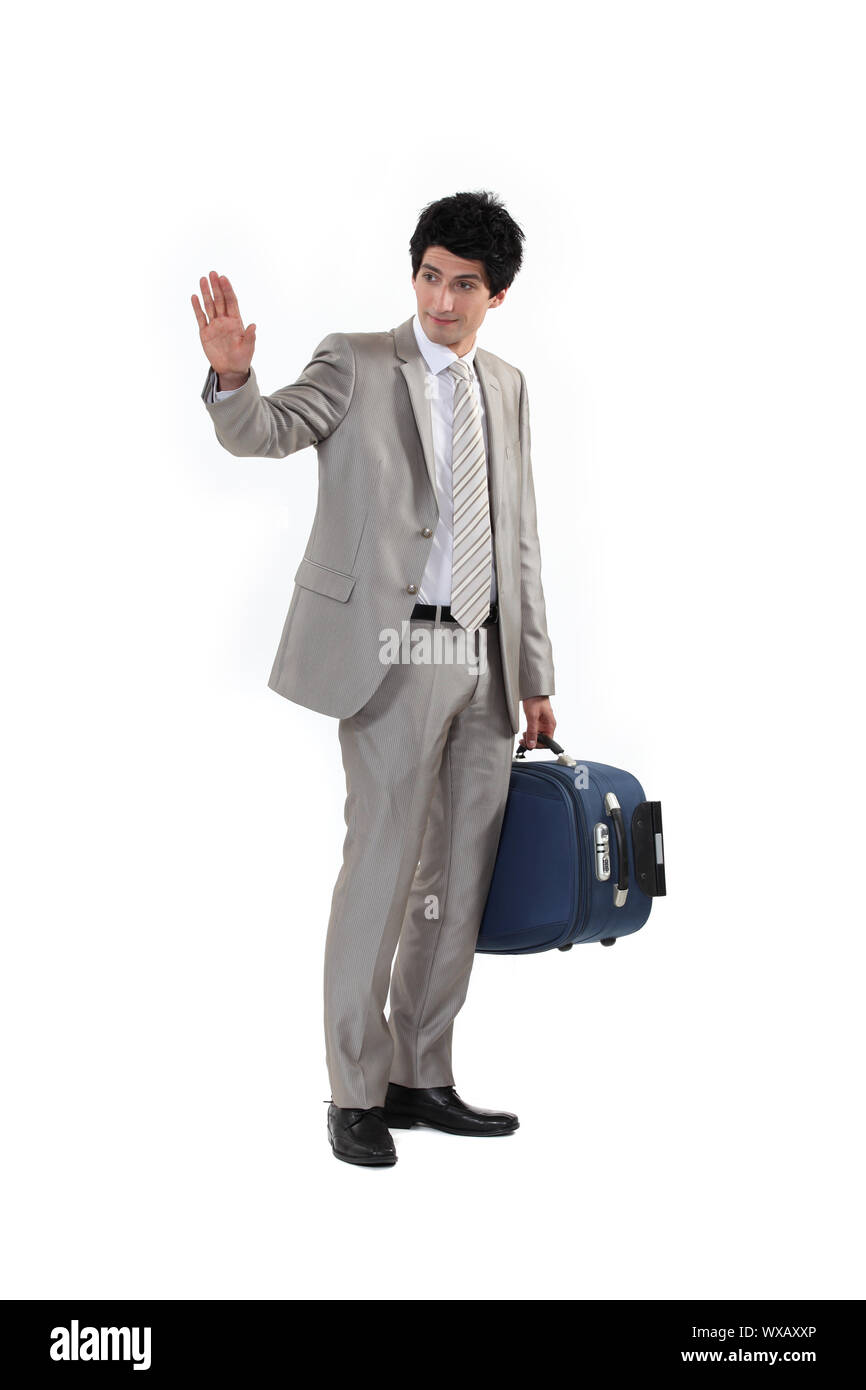 Man with suitcase waving goodbye Stock Photo - Alamy