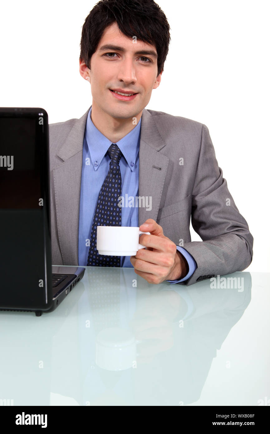 Worker drinking coffee in front of laptop Stock Photo - Alamy