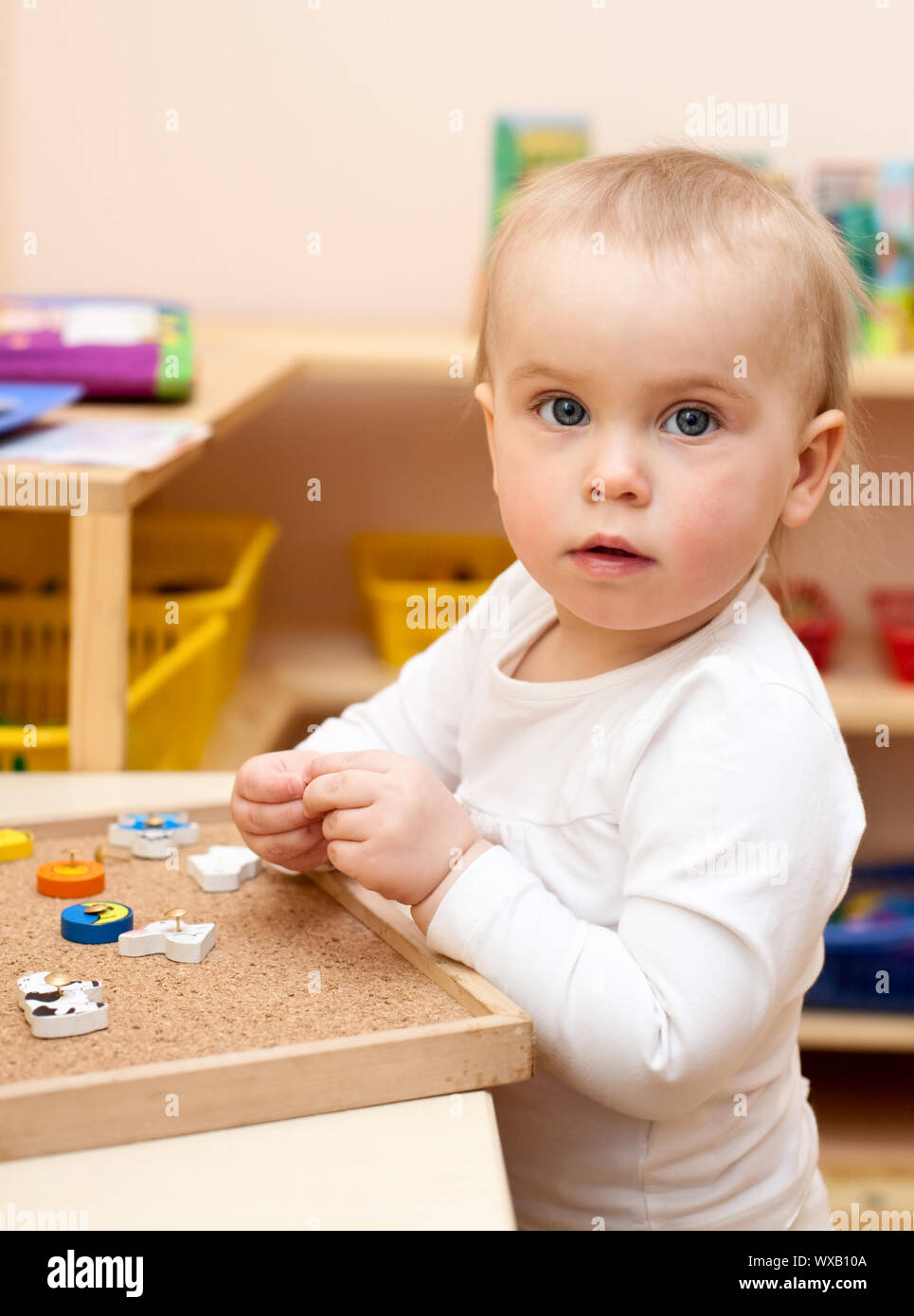Little baby girl playing with wooden toys at nursery Stock Photo - Alamy